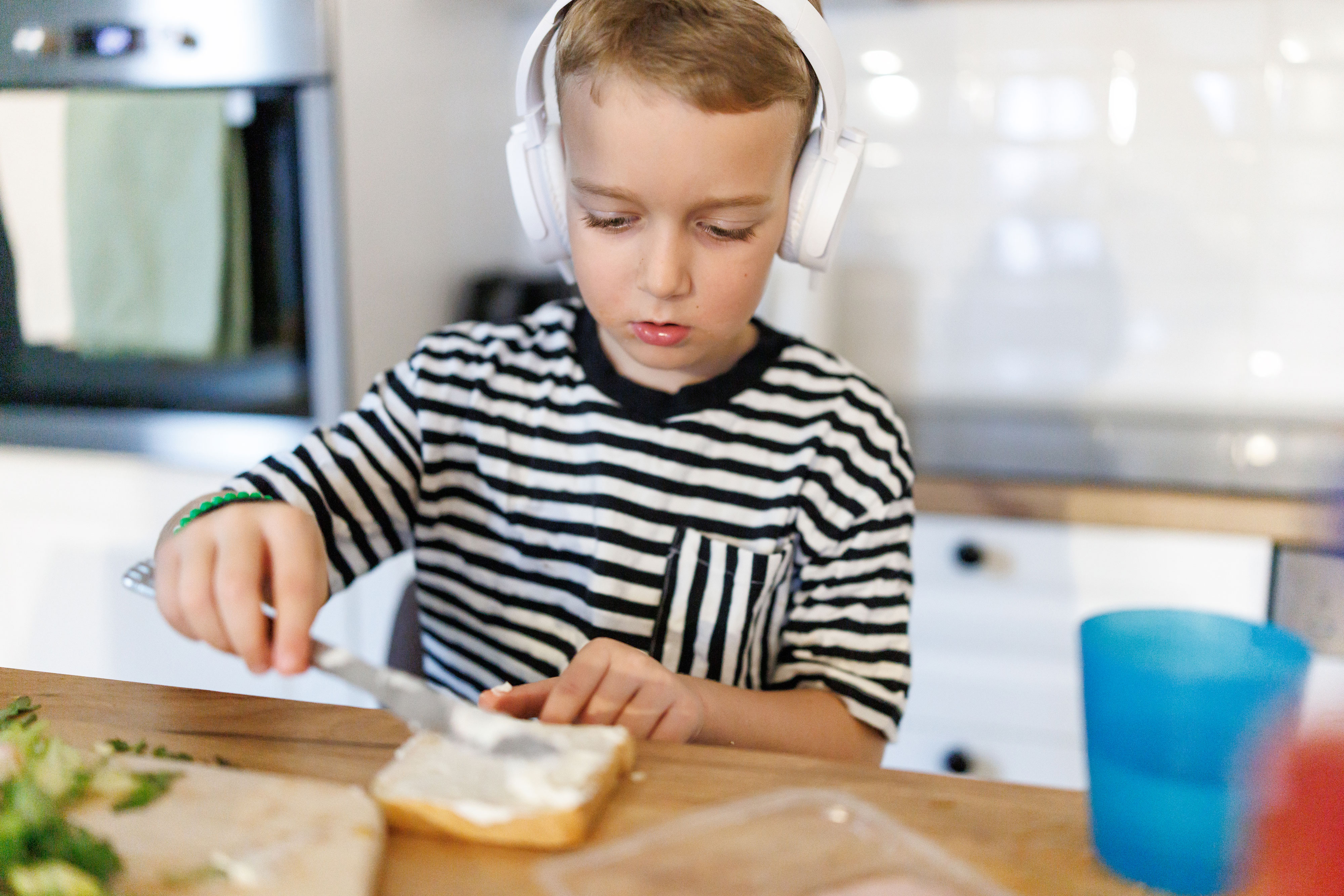 Boy making a sandwich while listening to music through headphones