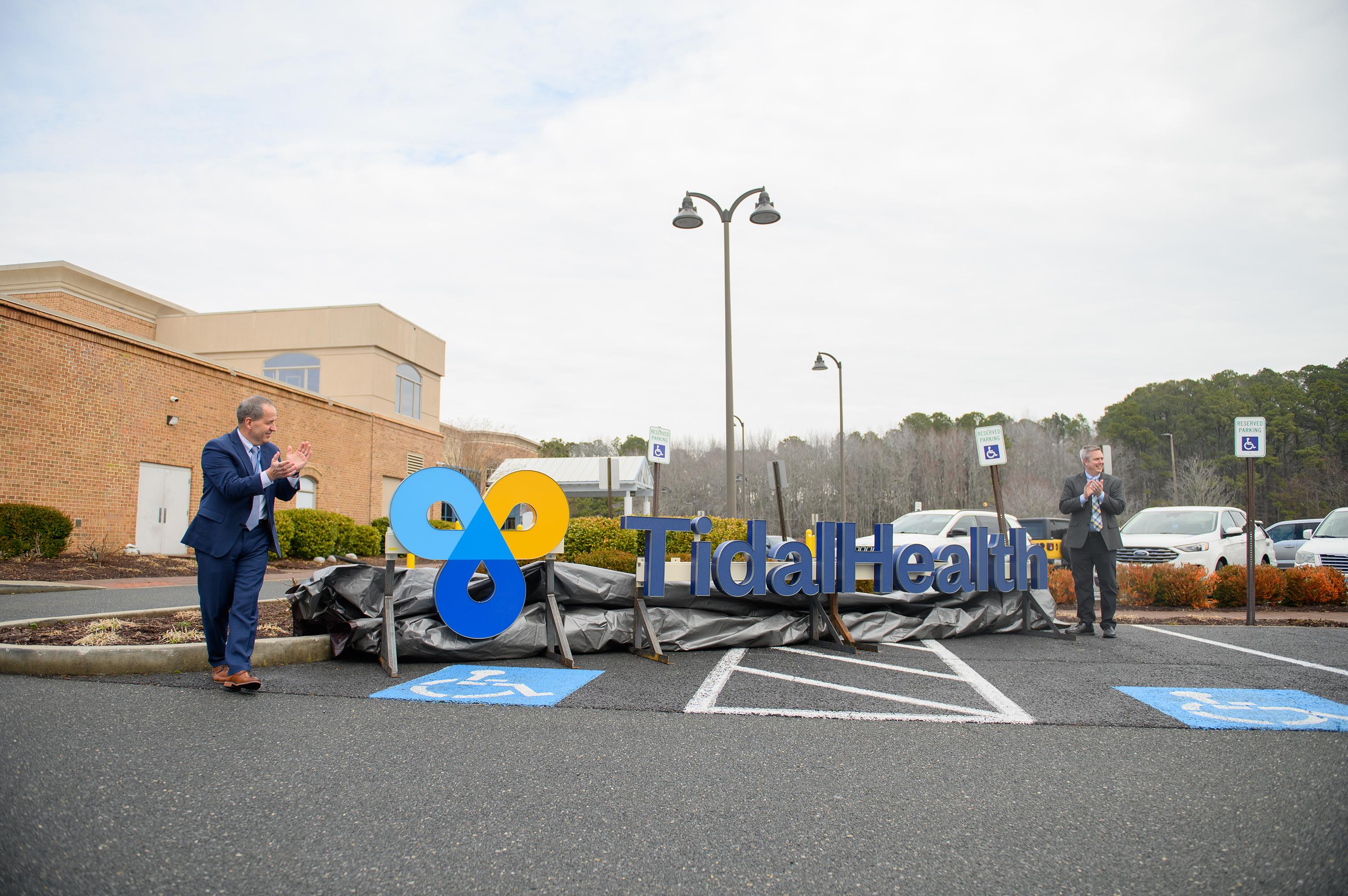 Two men unveil a large TidalHealth sign